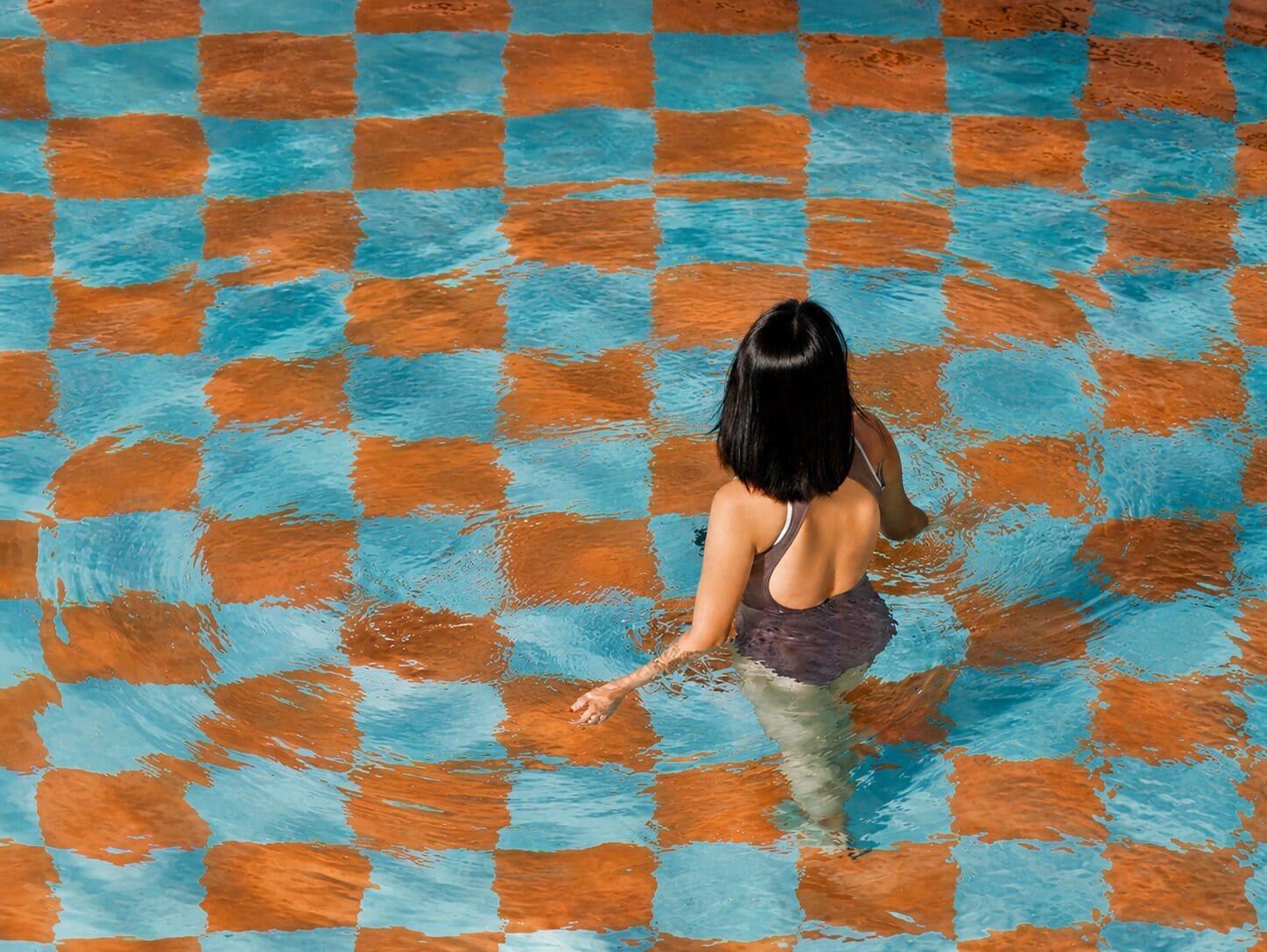 Uma pessoa em uma piscina com um padrão de piso quadriculado.