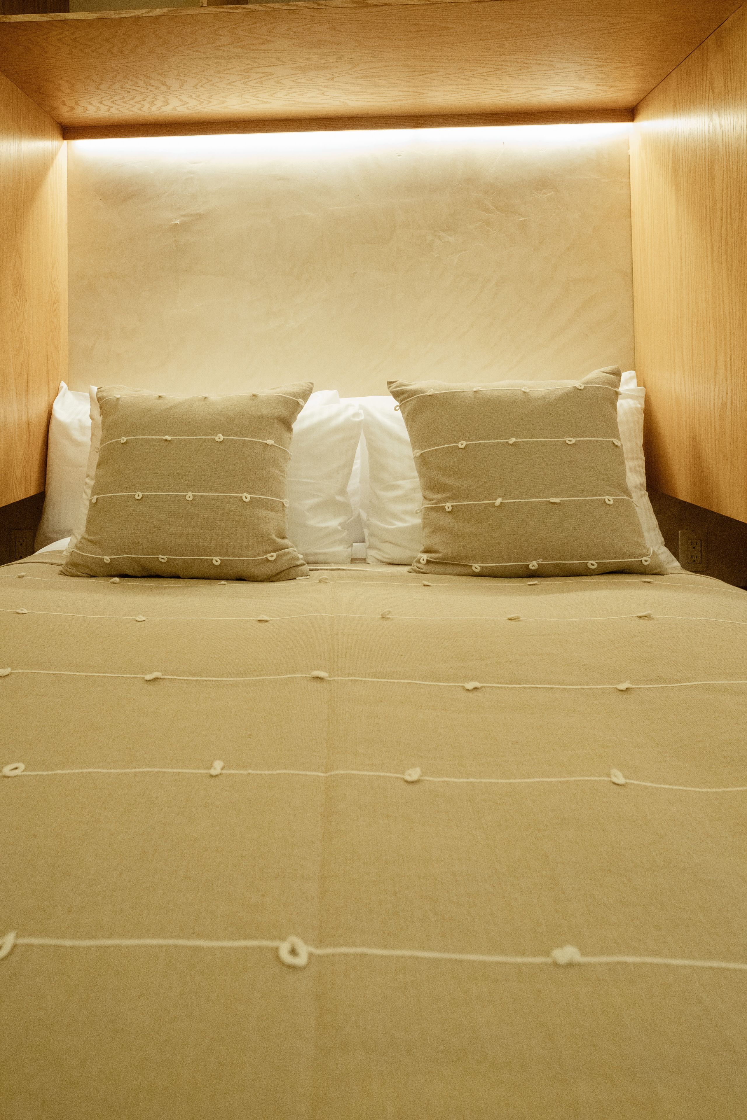 Uma cama com cabeceira, duas almofadas e um cobertor.