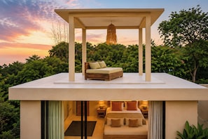Quarto moderno com cama sob um dossel, vista do céu e vegetação.