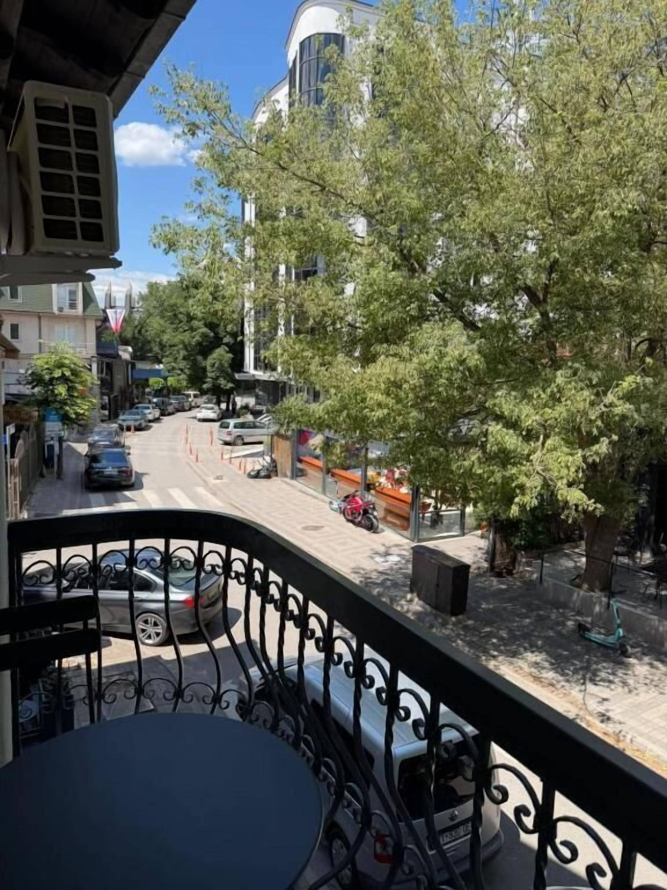 Varanda com vista para a rua, carros e árvores.
