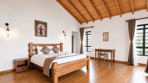 Quarto com cama de madeira, uma escrivaninha e uma janela com cortinas.