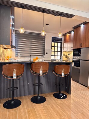 Uma cozinha moderna com uma ilha central, banquetas e eletrodomésticos embutidos.