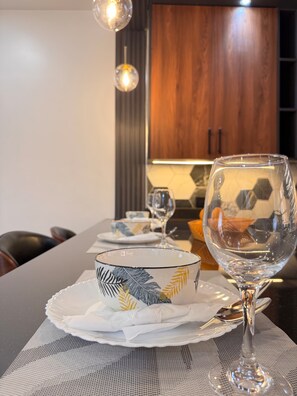 Uma mesa de jantar com uma taça de vinho de vidro e uma tigela com padrão de folha, sobre um jogo de mesa texturizado.