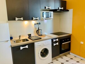 Uma cozinha compacta com máquina de lavar, micro-ondas e pia.
