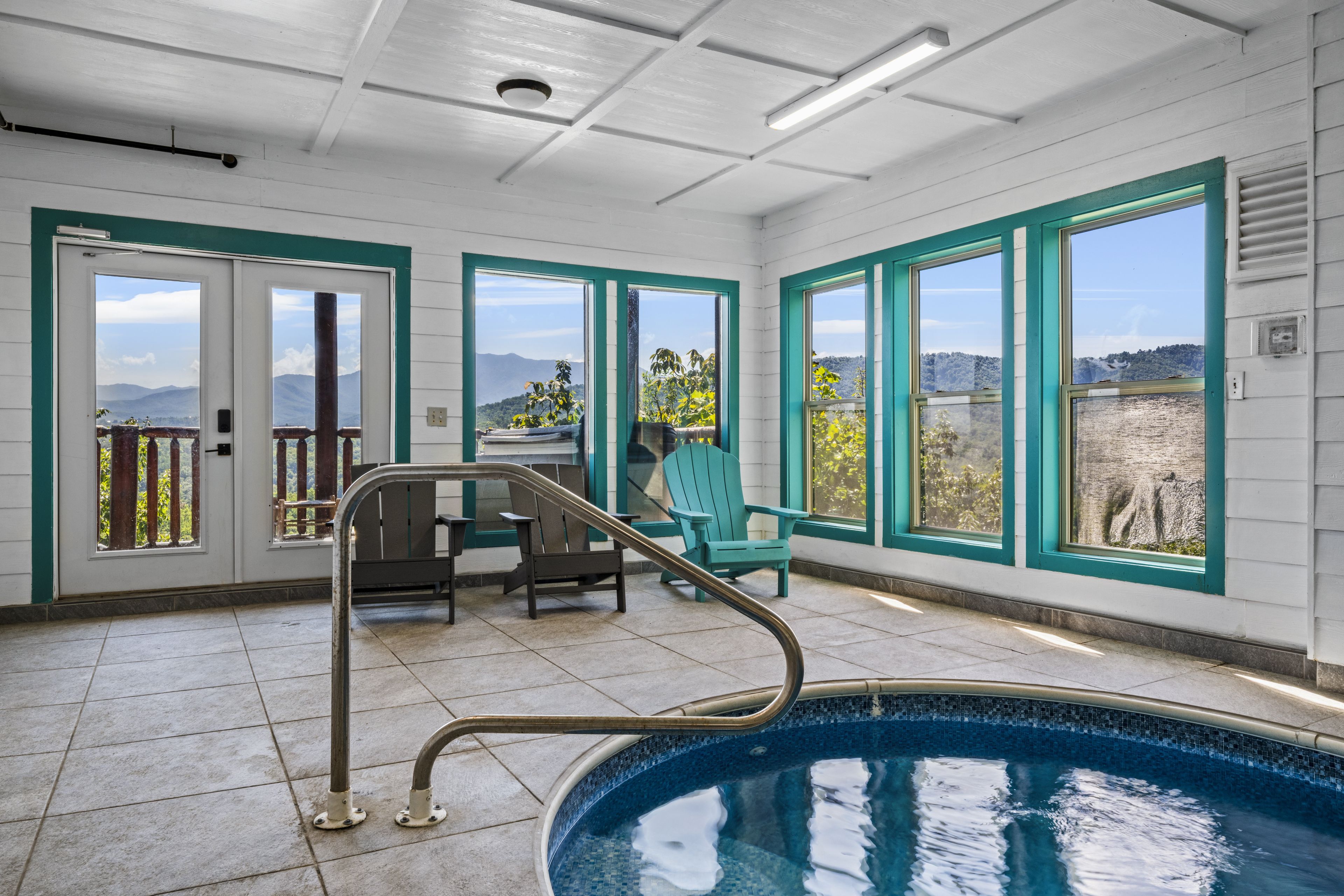 Área de piscina com vista para montanhas, uma cadeira e uma mesa.