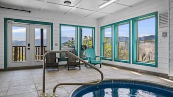 Área de piscina com vista para montanhas, uma cadeira e uma mesa.