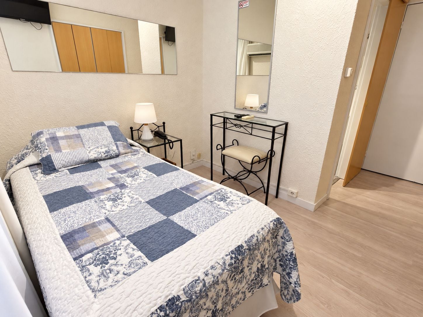 Quarto com cama, mesa de cabeceira, cadeira e espelho.
