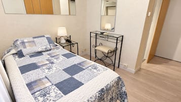 Quarto com cama, mesa de cabeceira, cadeira e espelho.