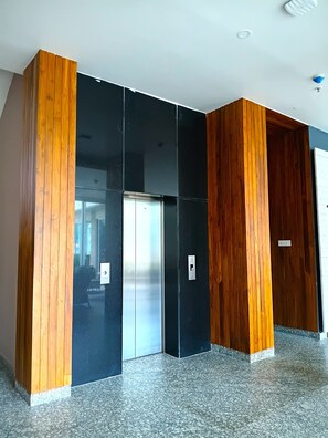 Um elevador em um edifício com design moderno, com detalhes em madeira e piso de granito.