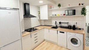 Uma cozinha moderna com armários brancos, fogão embutido, micro-ondas e máquina de lavar.