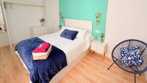 Quarto com cama, mesas de cabeceira, uma cadeira, ventilador de teto e luminária na parede.