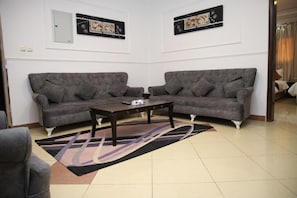 Uma sala de estar com dois sofás cinza, uma mesa de centro de madeira escura e um tapete estampado.