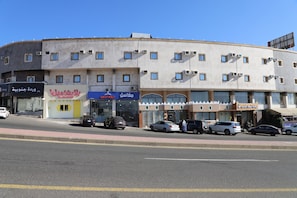 Um edifício de vários andares com diversos espaços comerciais na base, incluindo uma loja de roupas e um café.