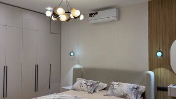 Quarto moderno com cama grande, luminária de teto e ar condicionado.