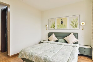 Quarto com uma cama, duas luminárias na parede e três impressões botânicas emolduradas.