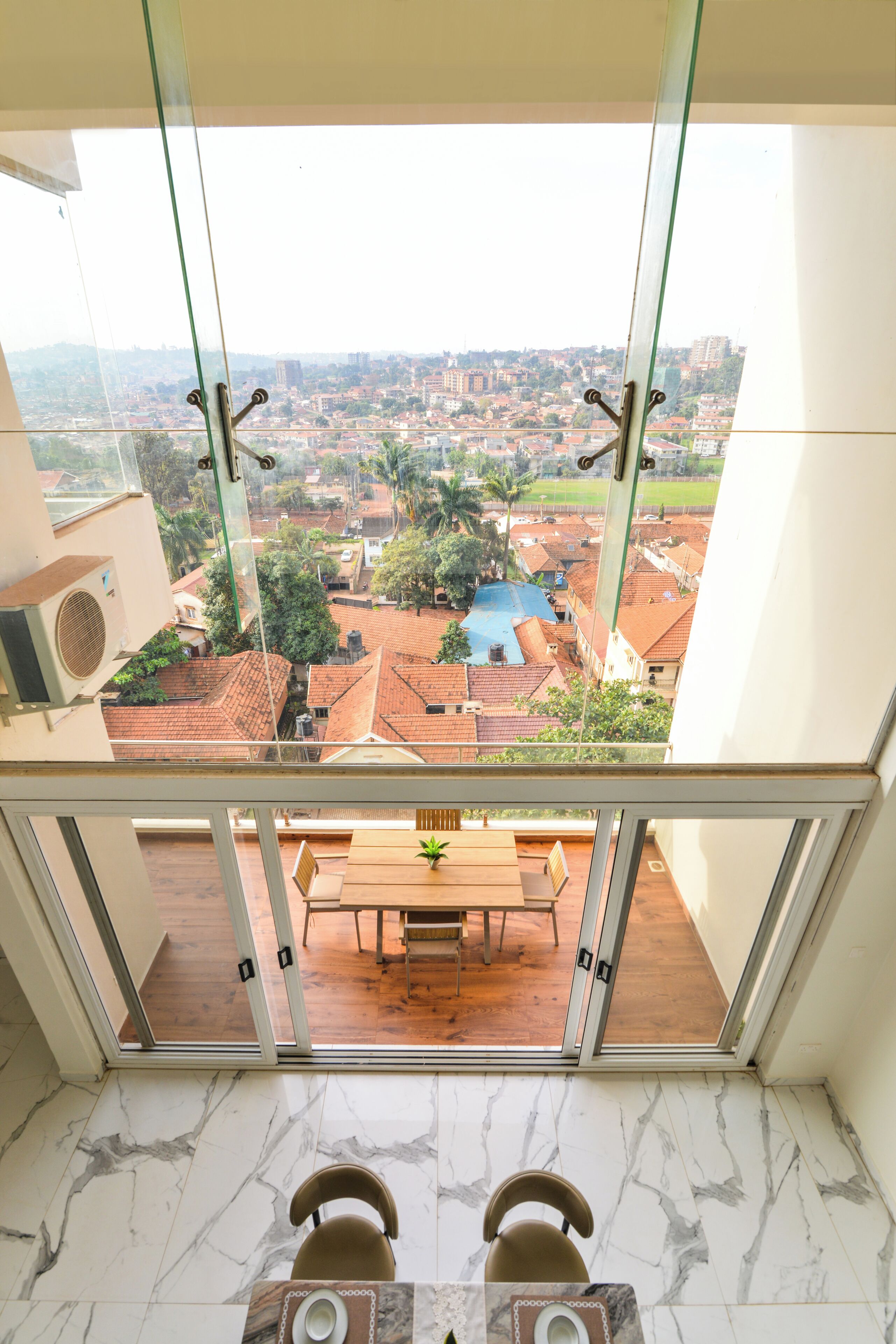 Um apartamento alto com varanda de vidro e vista para a paisagem urbana.