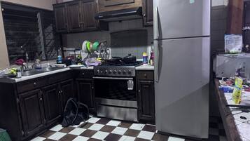 Cozinha equipada com geladeira, fogão, forno e lava-louças.