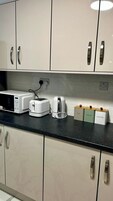 Uma cozinha com armários brancos, micro-ondas, torradeira e cafeteira.