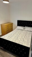 Um quarto com uma cama, uma cômoda de madeira e uma luminária no teto.