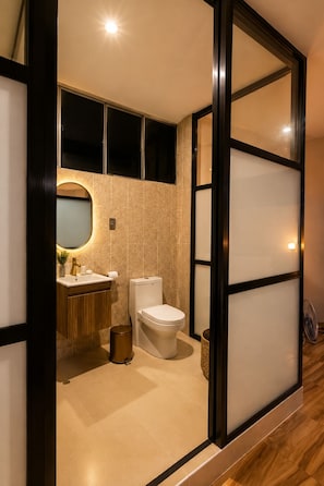 Uma casa de banho moderna com sanita, lavatório e espelho.