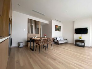 Um espaço de estar moderno com área de jantar, sofá, televisão e cozinha.