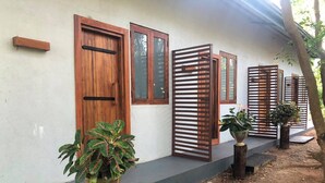 Um edifício com portas e janelas de madeira, um caminho de concreto e plantas em vasos.