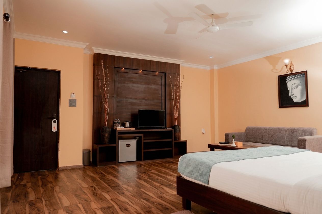 Quarto de hotel com cama, televisão, sofá e ventoinha no teto.