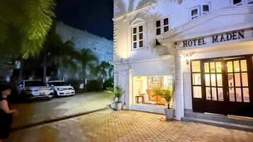 Um hotel com fachada clássica, entrada bem iluminada e acesso por um caminho de paralelepípedos.
