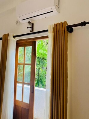 Quarto com janela, cortinas e ar condicionado.