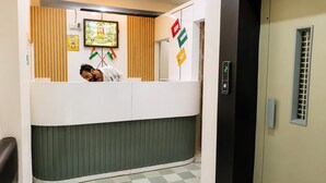 Uma área de recepção com balcão, televisão montada acima e uma porta com janela.