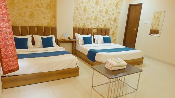 Quarto de hotel com duas camas, uma mesa pequena e uma porta.