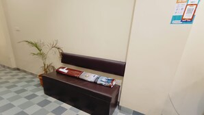 Piso xadrez, um banco, um vaso de planta e uma parede com um aviso.