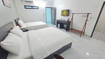 Quarto de hotel com duas camas, uma escrivaninha, uma cadeira, uma televisão e um porta-roupas.