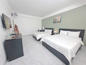 Quarto de hotel com duas camas, uma escrivaninha, uma cadeira, uma televisão e um quadro na parede.