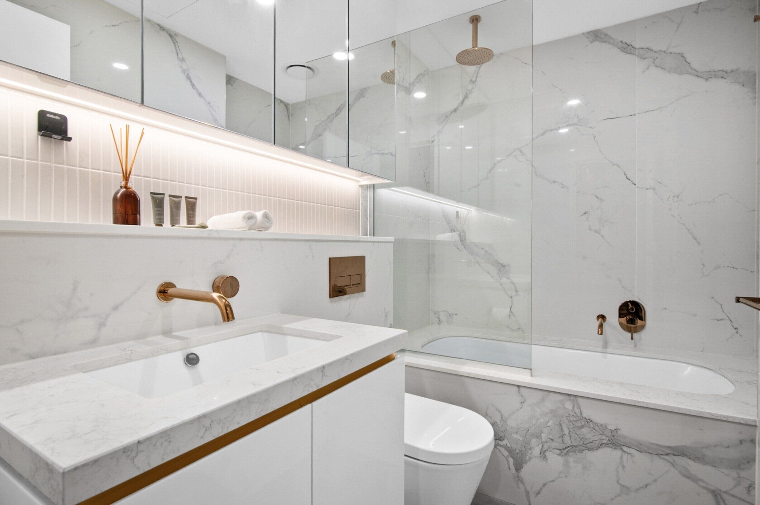 Uma casa de banho moderna com lavatório de mármore, banheira e zona de duche com proteção de vidro.