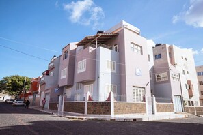 Um edifício residencial de vários andares com parede de pedra e portão branco.