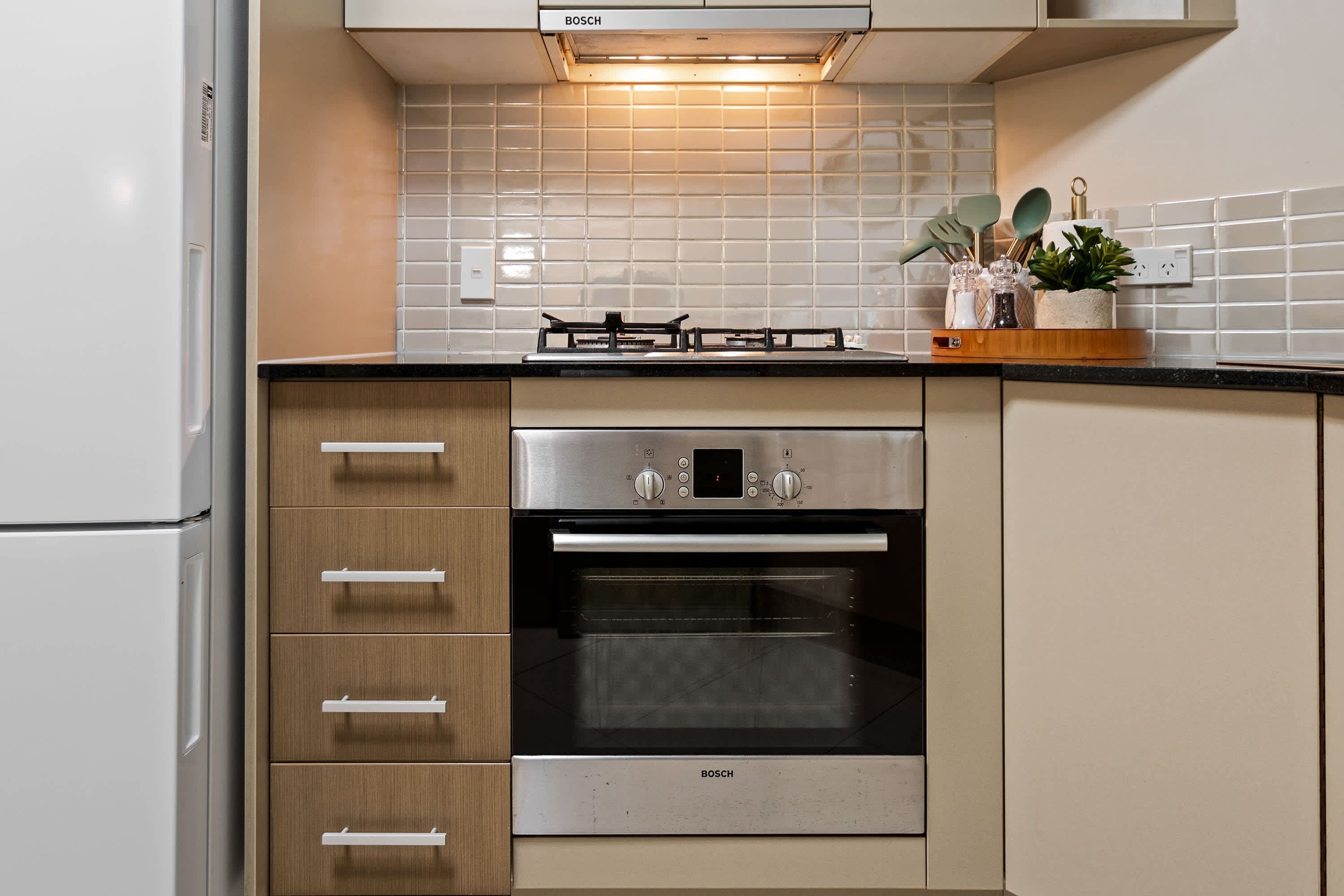 Uma cozinha com forno Bosch, fogão embutido e geladeira.