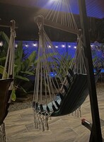 Uma cadeira-rede com base de rede, com vista para uma piscina e plantas.
