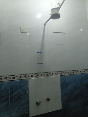 Um banheiro com chuveiro, porta-toalhas e luminária na parede.