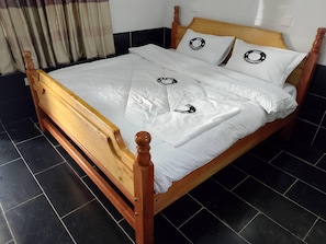 Uma cama com estrutura de madeira, roupa de cama branca e almofadas com um logotipo.