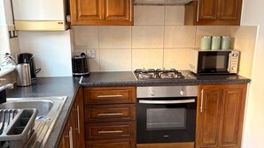 Uma cozinha com armários de madeira, fogão a gás, micro-ondas e máquina de lavar louça.