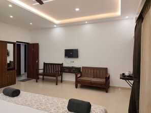 Uma sala de estar moderna com um sofá, uma cadeira de madeira, uma TV de tela plana na parede e uma mesinha com um tabuleiro.