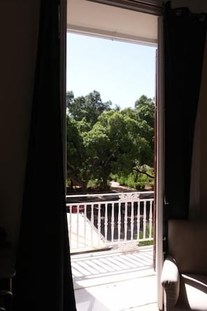 Quarto com vista para uma varanda e árvores.