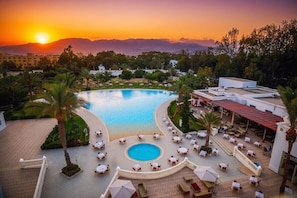 Um resort com uma piscina grande, área de estar externa e vista para o pôr do sol.