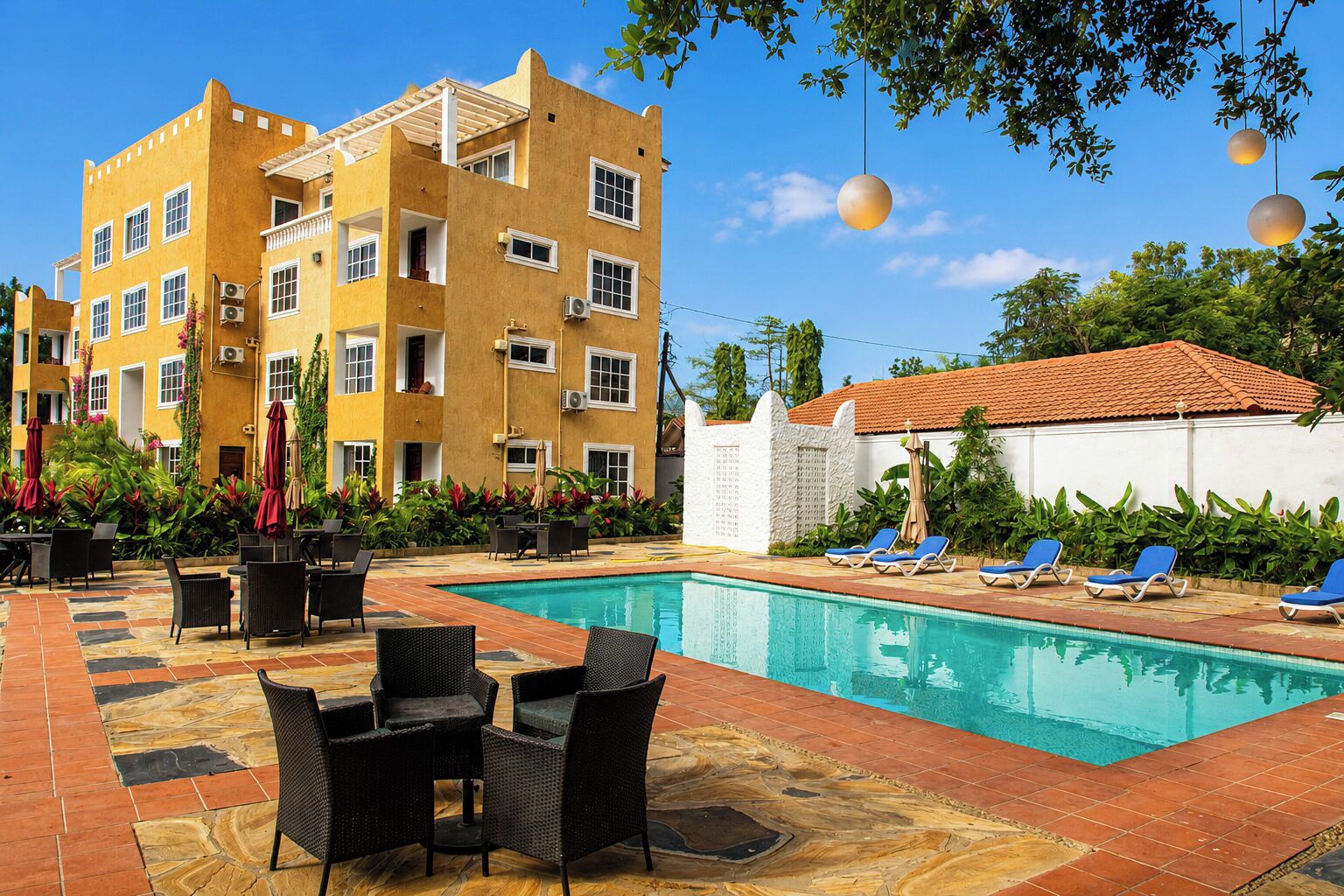 Um hotel com piscina, área de estar externa e parede branca com telhado telhado.