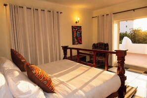 Quarto de hotel com cama, cortinas, um quadro, uma cadeira e varanda com vista.