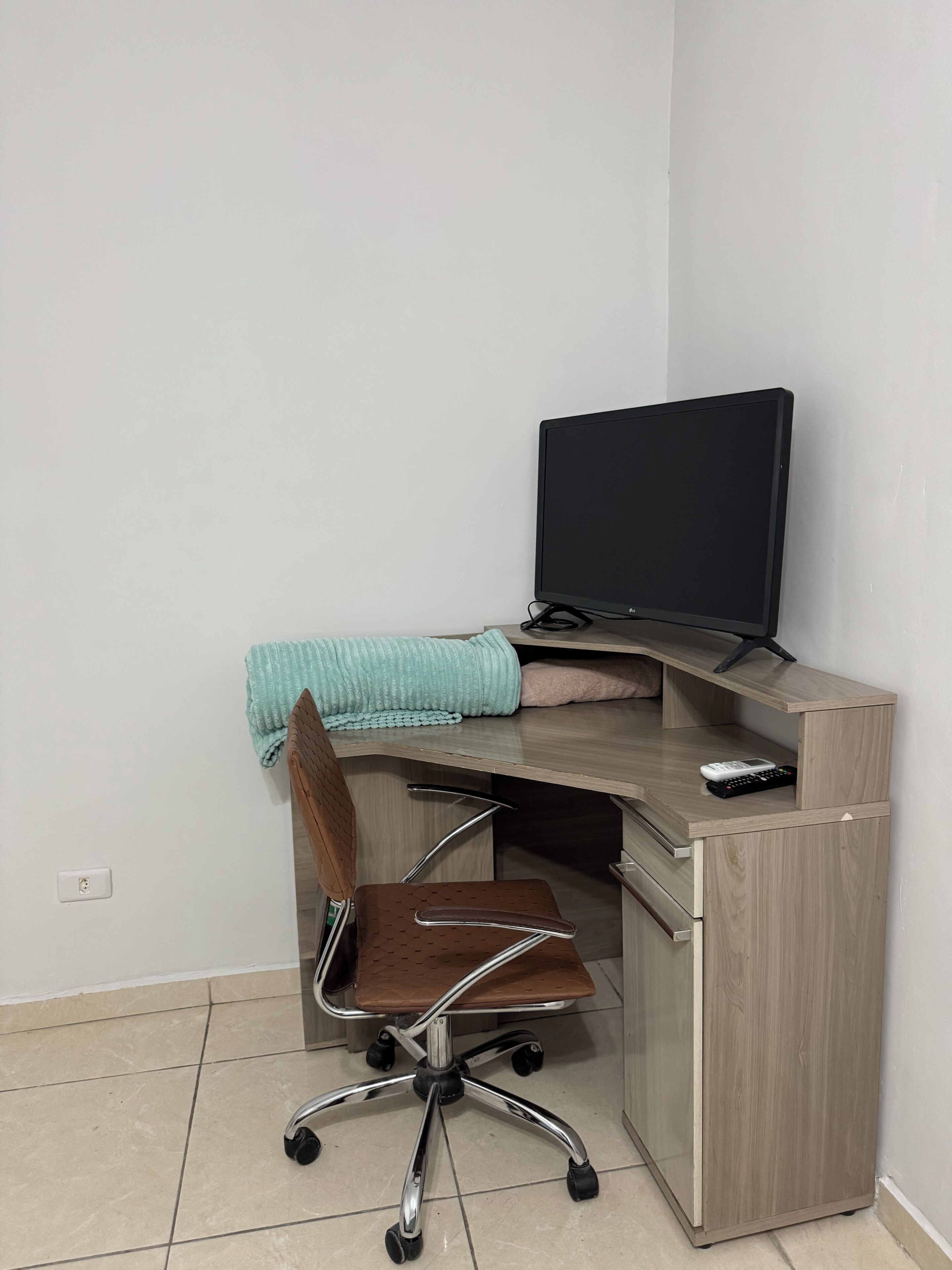 Escritório de canto com secretária, cadeira e monitor de computador.