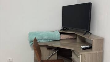 Escritório de canto com secretária, cadeira e monitor de computador.