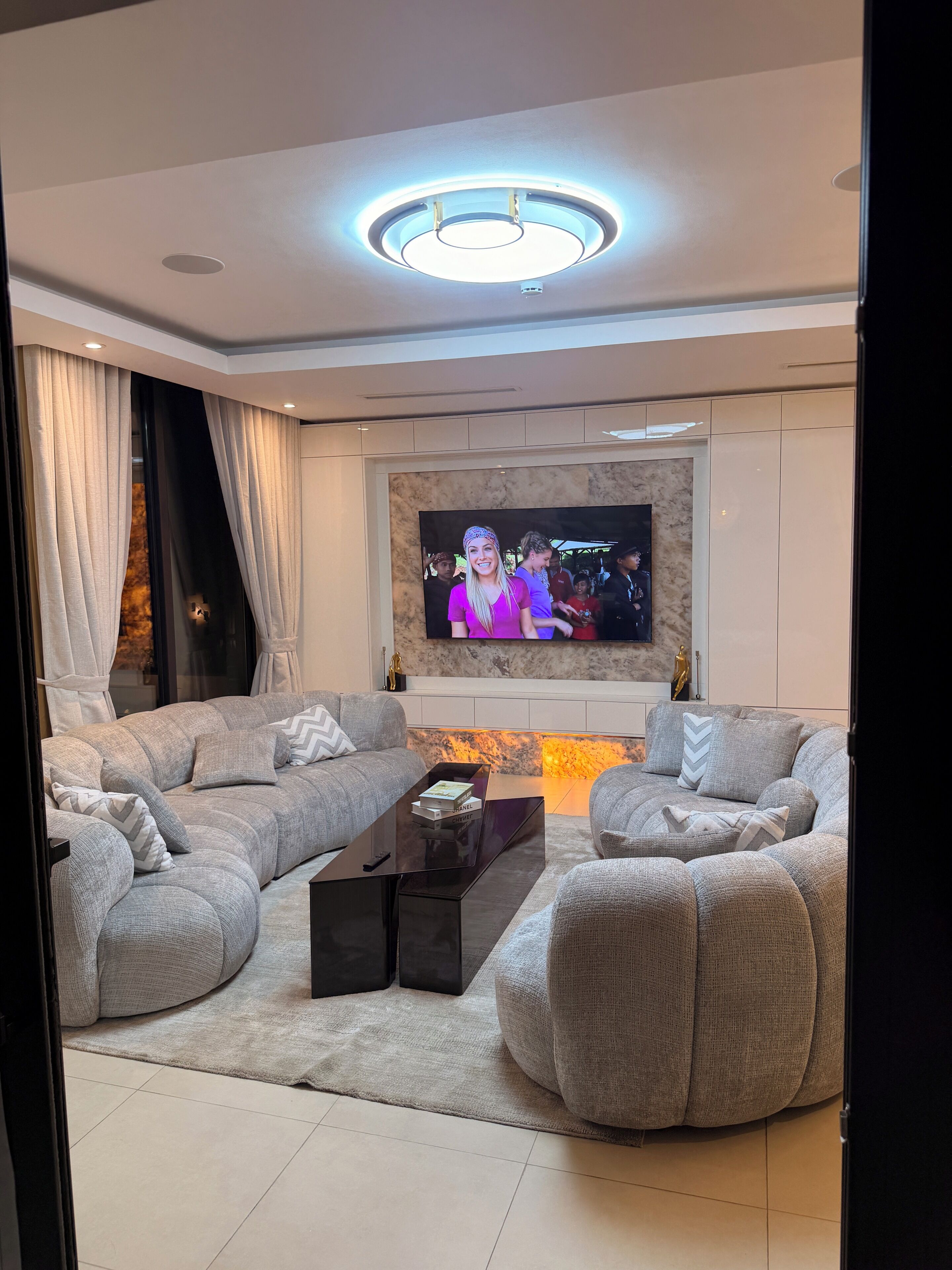 Uma sala de estar moderna com um sofá seccional, uma TV de tela plana e uma parede de destaque em mármore.