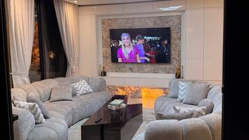 Uma sala de estar moderna com um sofá seccional, uma TV de tela plana e uma parede de destaque em mármore.
